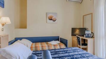 Quarto de hotel com cama, escrivaninha, cadeira, ar condicionado e um quadro na parede.