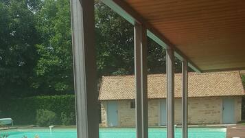 Uma área externa coberta com piscina, espreguiçadeiras e vasos de plantas.