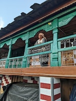 Um edifício tradicional com varandas de madeira verde e entalhes elaborados.