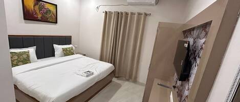 Quarto de hotel moderno com uma cama grande, um ventilador de teto, um ar condicionado e área de chuveiro.