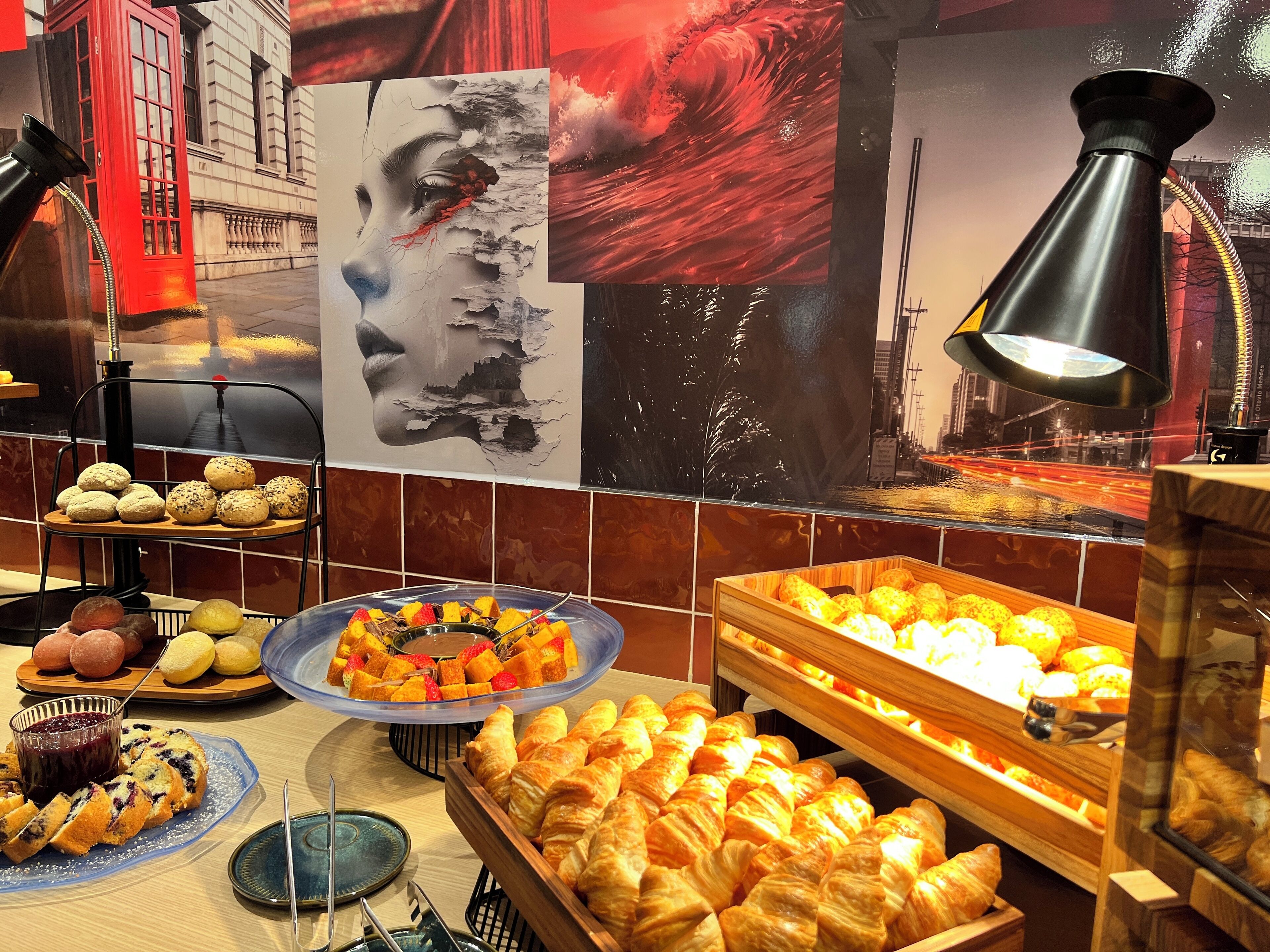 Buffet de café da manhã com diversos pães, frutas e doces.