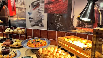 Buffet de café da manhã com diversos pães, frutas e doces.