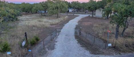 Uma trilha de cascalho leva a uma área cercada, com cerca e um poste de sinalização.