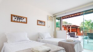 Quarto de hotel com duas camas, uma janela grande e vista para a área externa.