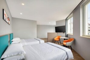 Quarto de hotel com duas camas, uma escrivaninha, duas cadeiras, uma televisão e uma janela.