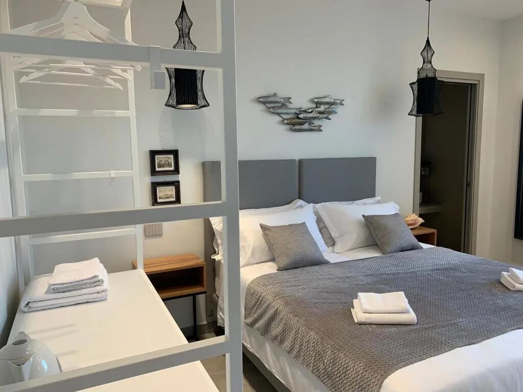 Quarto moderno com cama grande, mesas de cabeceira e um elemento decorativo na parede.