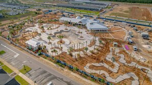 Vista aérea de um grande complexo comercial com vários edifícios, áreas de estacionamento e espaços ajardinados.