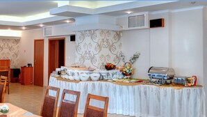 Espaço de refeições com buffet, incluindo churrasqueira, torradeira e diversos alimentos.