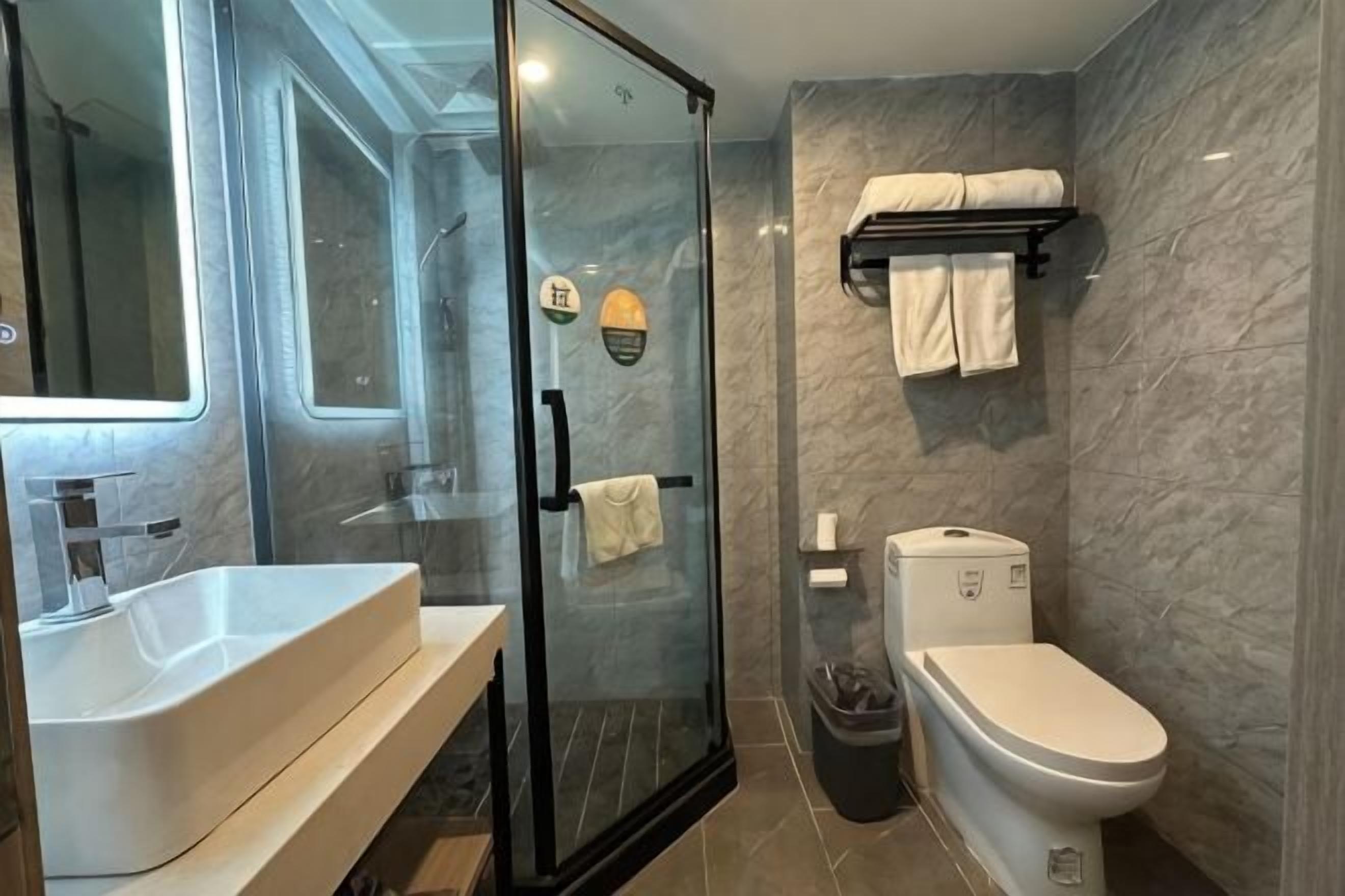 Uma casa de banho moderna com cabine de duche em vidro, lavatório branco e sanita.