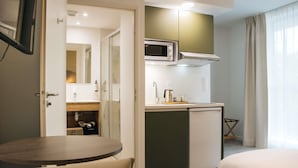 Quarto de hotel compacto com cozinha compacta, uma pequena mesa de jantar e uma cama.
