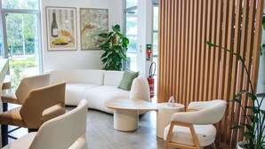 Um interior moderno com um sofá branco, cadeiras, uma mesa de centro redonda e um vaso de planta.