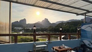 Um terraço com mesa, cadeiras e vista para montanhas e para a cidade.