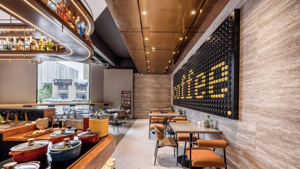 Interior moderno de restaurante com área de bar, mesas de jantar e adega embutida na parede.