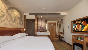 Quarto de hotel com uma cama grande, um mapa na parede, uma televisão e um banheiro visível através de uma porta aberta.