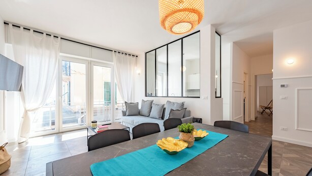 Uma sala de jantar moderna com mesa de mármore, corredor azul-turquesa e tigelas decorativas.