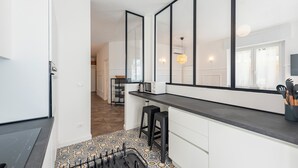 Uma cozinha moderna com bancada escura, armários brancos e piso estampado.