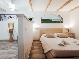 Quarto com cama, mesas de cabeceira, luminária, quadro e arandela.