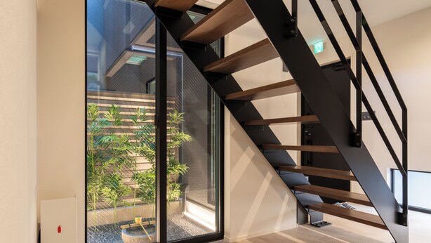Escadaria moderna com porta de vidro que dá para área externa com plantas.