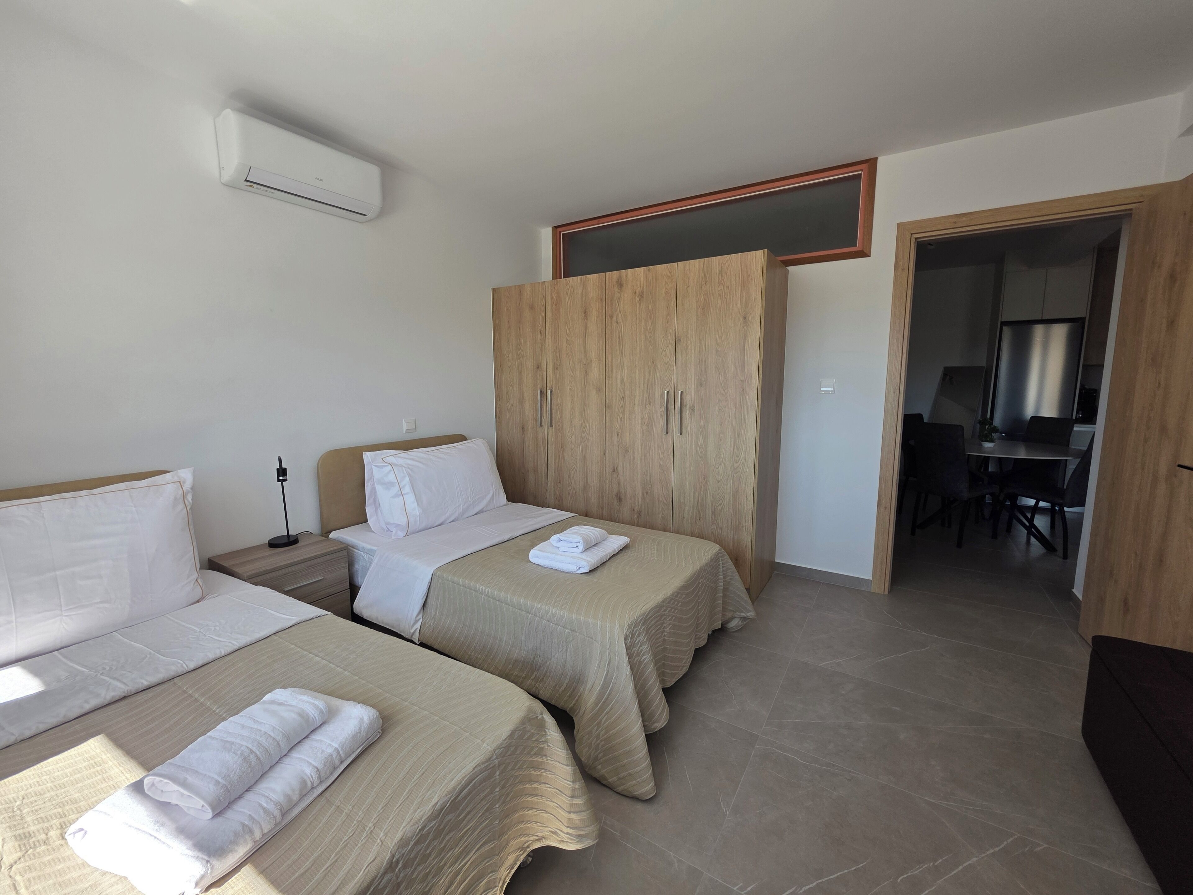 Quarto de hotel com duas camas, uma escrivaninha e um guarda-roupa.