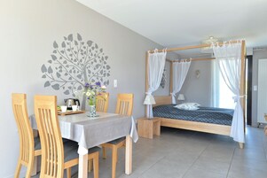 Um quarto com cama de dossel, uma mesa de jantar com cadeiras e um mural na parede.