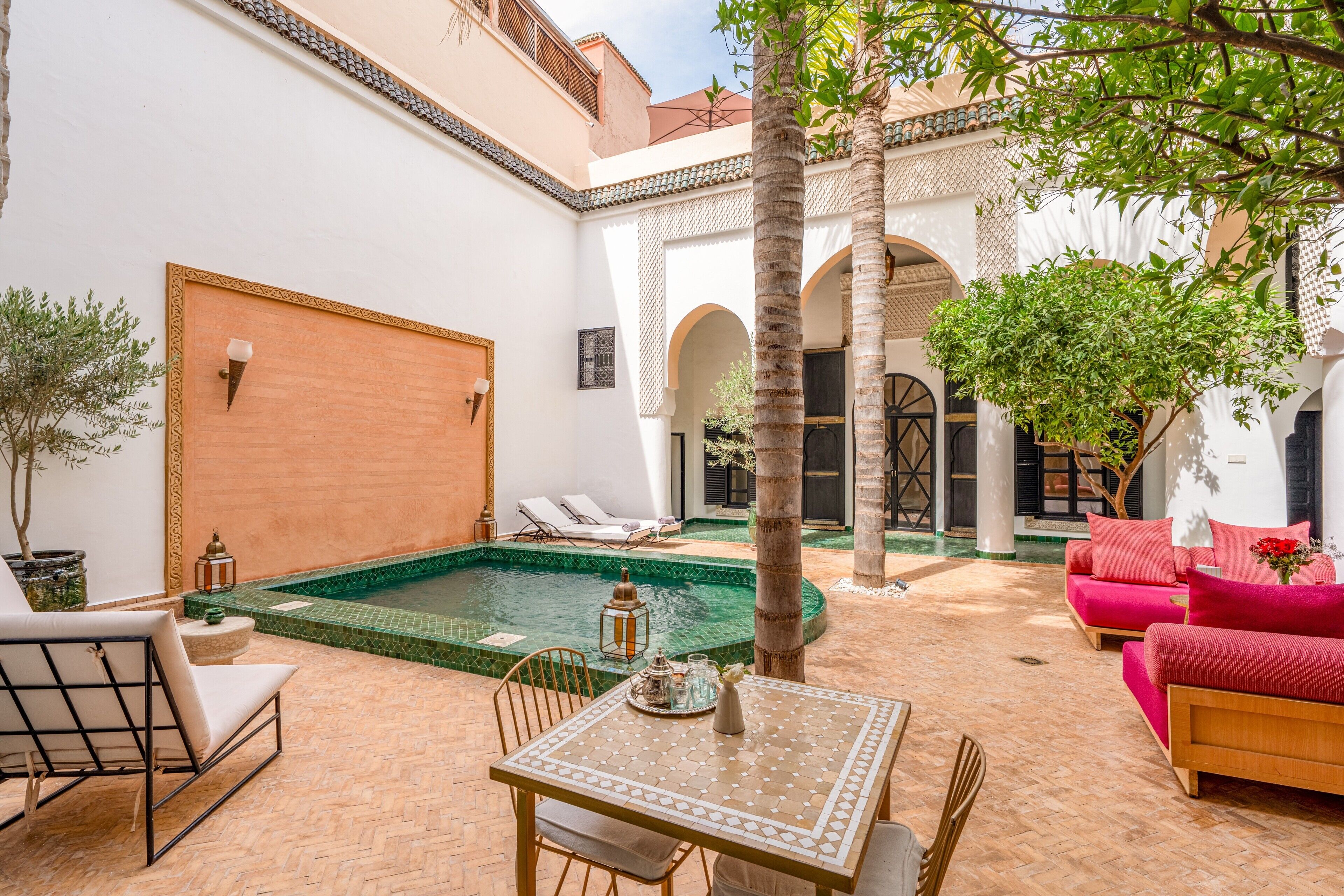 Um pátio com piscina, espreguiçadeiras, mesa e sofá.