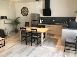 Uma cozinha moderna com uma mesa e cadeiras de madeira, uma coifa preta e um relógio na parede.