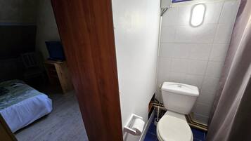 Um banheiro pequeno e compacto, com vaso sanitário, cortina de chuveiro e pia.