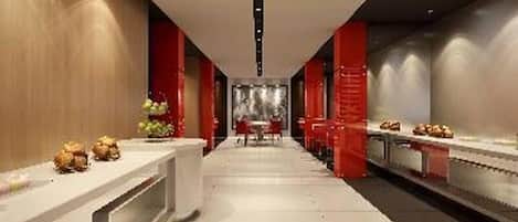 Corredor moderno de hotel com um longo balcão de recepção, detalhes em vermelho e uma área de estar central.