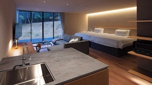 Quarto de hotel moderno com cozinha, sofá, cama e televisão.