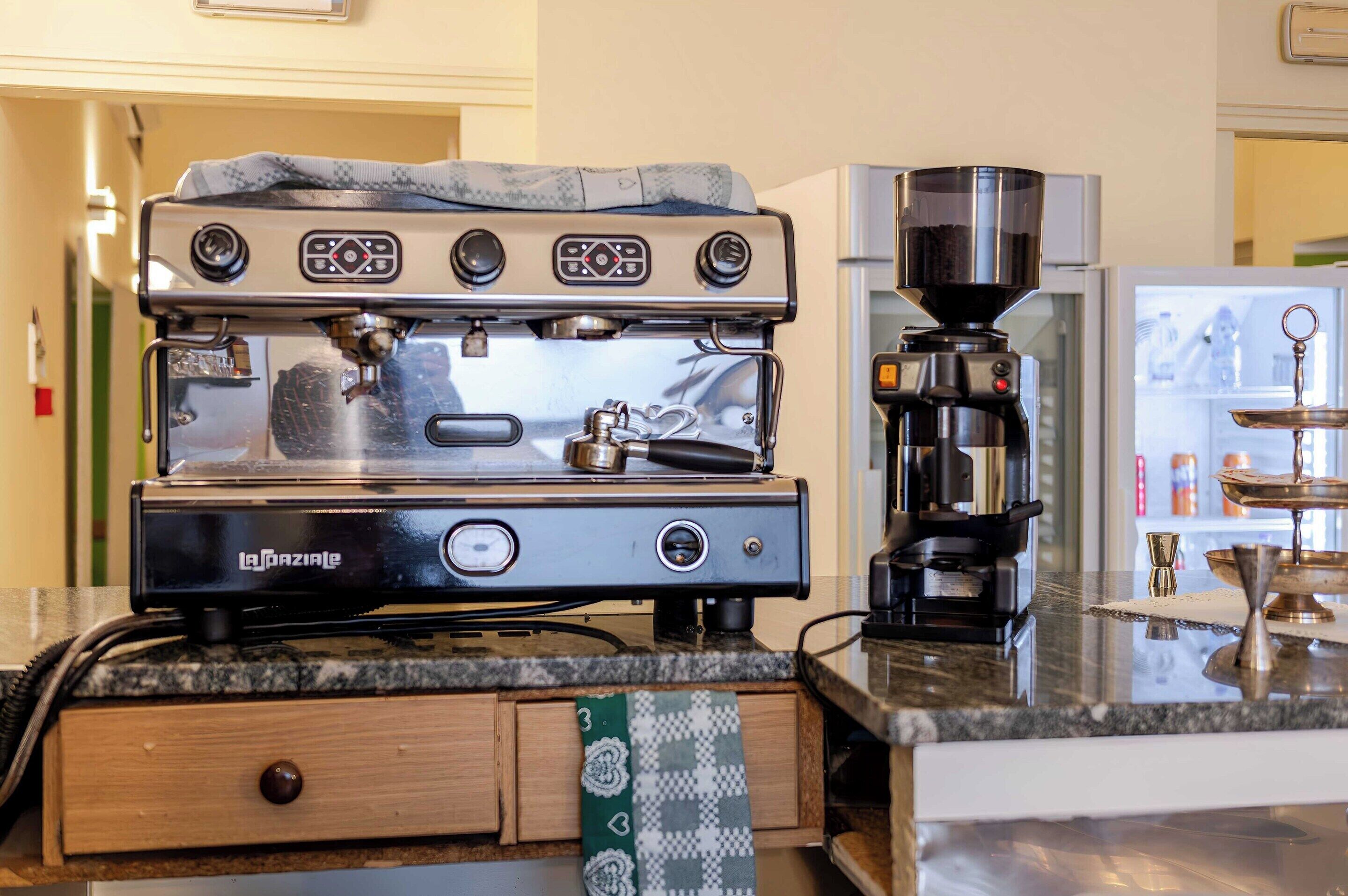 Máquina de espresso A La Pizzeria em uma cozinha com geladeira e moedor de café.