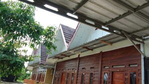 Uma fileira de edifícios de madeira com uma galeria coberta e uma árvore ao primeiro plano.