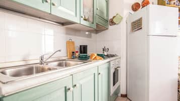 Um frigorífico, um forno, uma placa de cozinha, uma cafeteira/bule