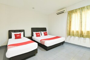 Quarto de hotel com duas camas, cada uma com cabeceira preta e roupa de cama branca com detalhes vermelhos.