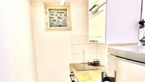 Cozinha compacta com bancada de madeira, pia, fogão e lixeira.