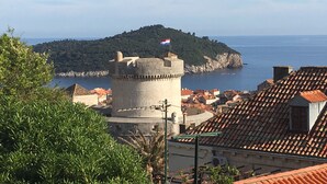 Uma vila costeira com uma torre imponente e uma bandeira no topo de uma colina.