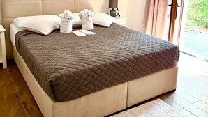 Cama bem arrumada com cobertura marrom acolchoada, abajur e mesa de cabeceira com luminária.