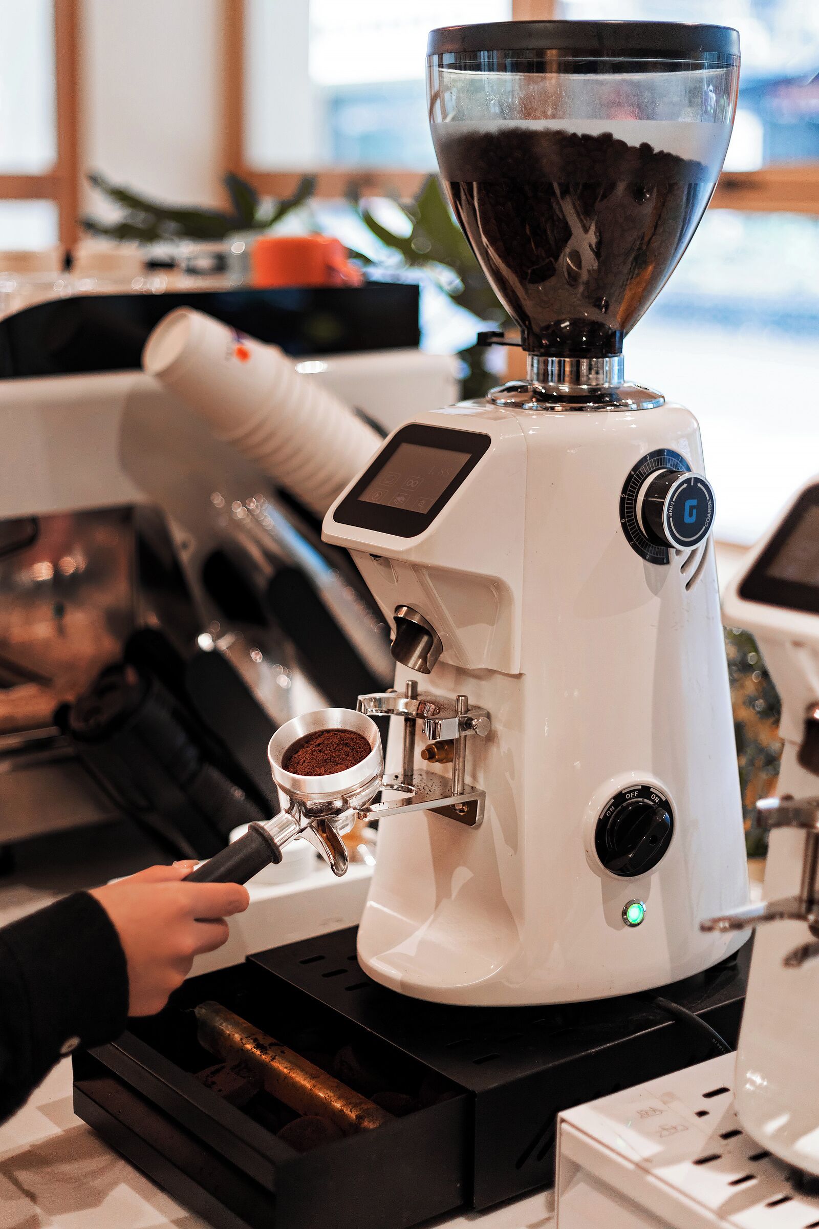 Uma máquina de café com visor digital, moedor e porta-filtro.