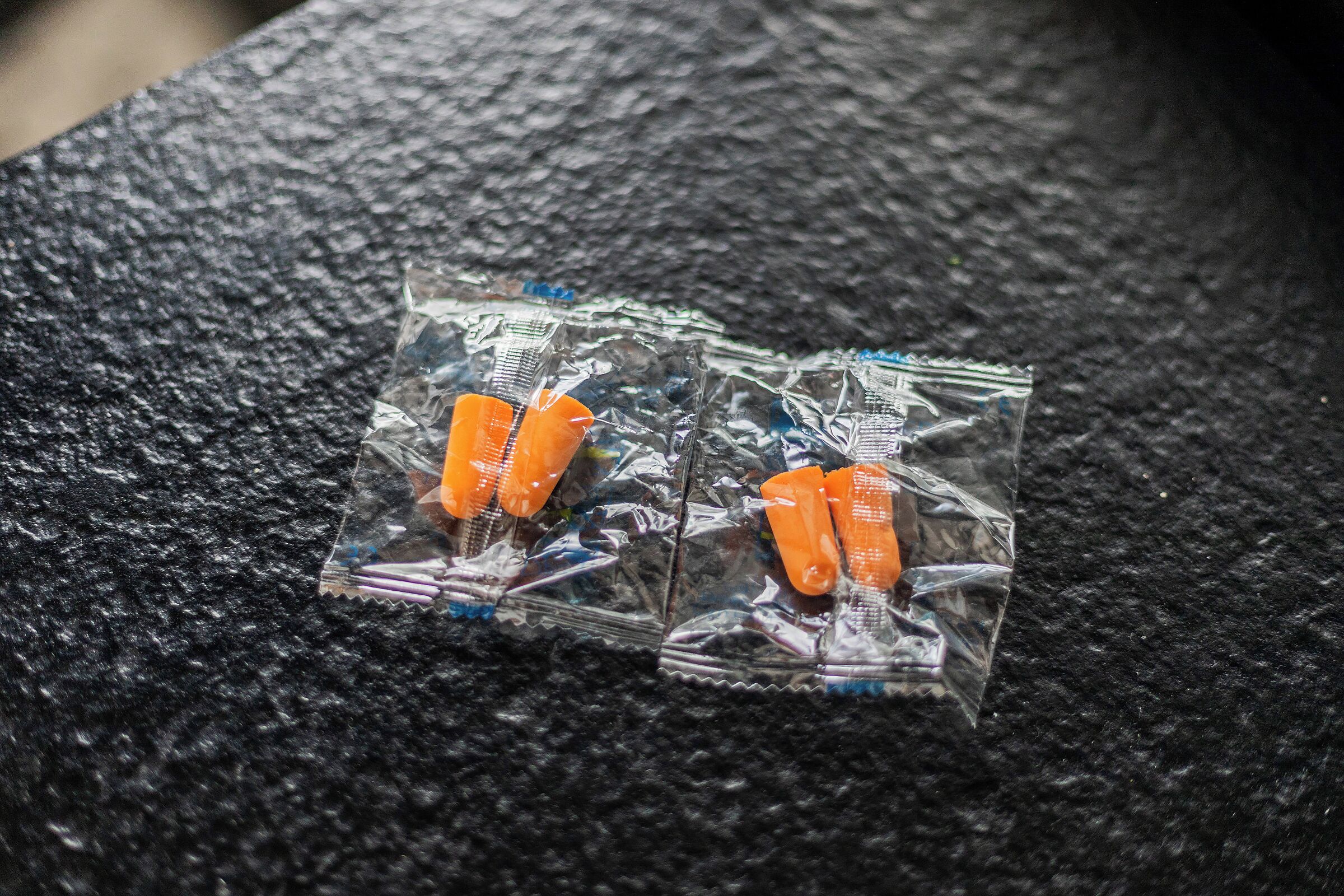 Duas embalagens de plástico transparente com conteúdo laranja e azul sobre uma superfície texturizada.