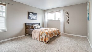 Quarto com cama, janela e um objeto decorativo fixado na parede.