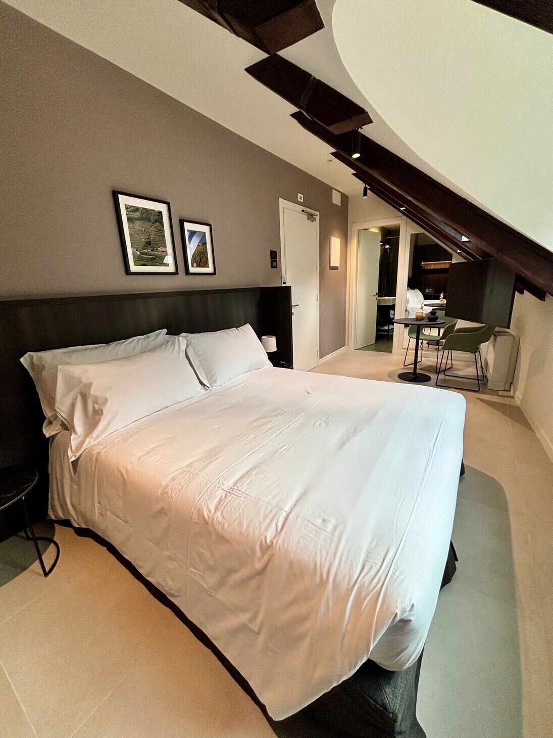 Quarto de hotel moderno com uma cama grande, uma escrivaninha e um espaço de refeições.