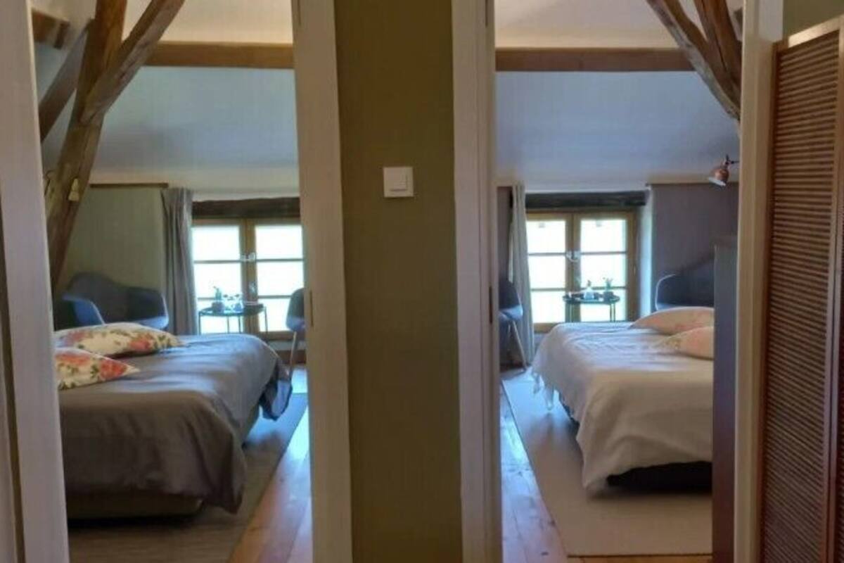 Quarto com duas camas, teto de madeira e janela.