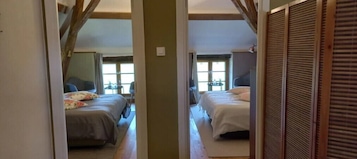 Quarto com duas camas, teto de madeira e janela.