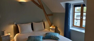 Quarto com cama grande, mesa de cabeceira, abajur e janela com cortinas.