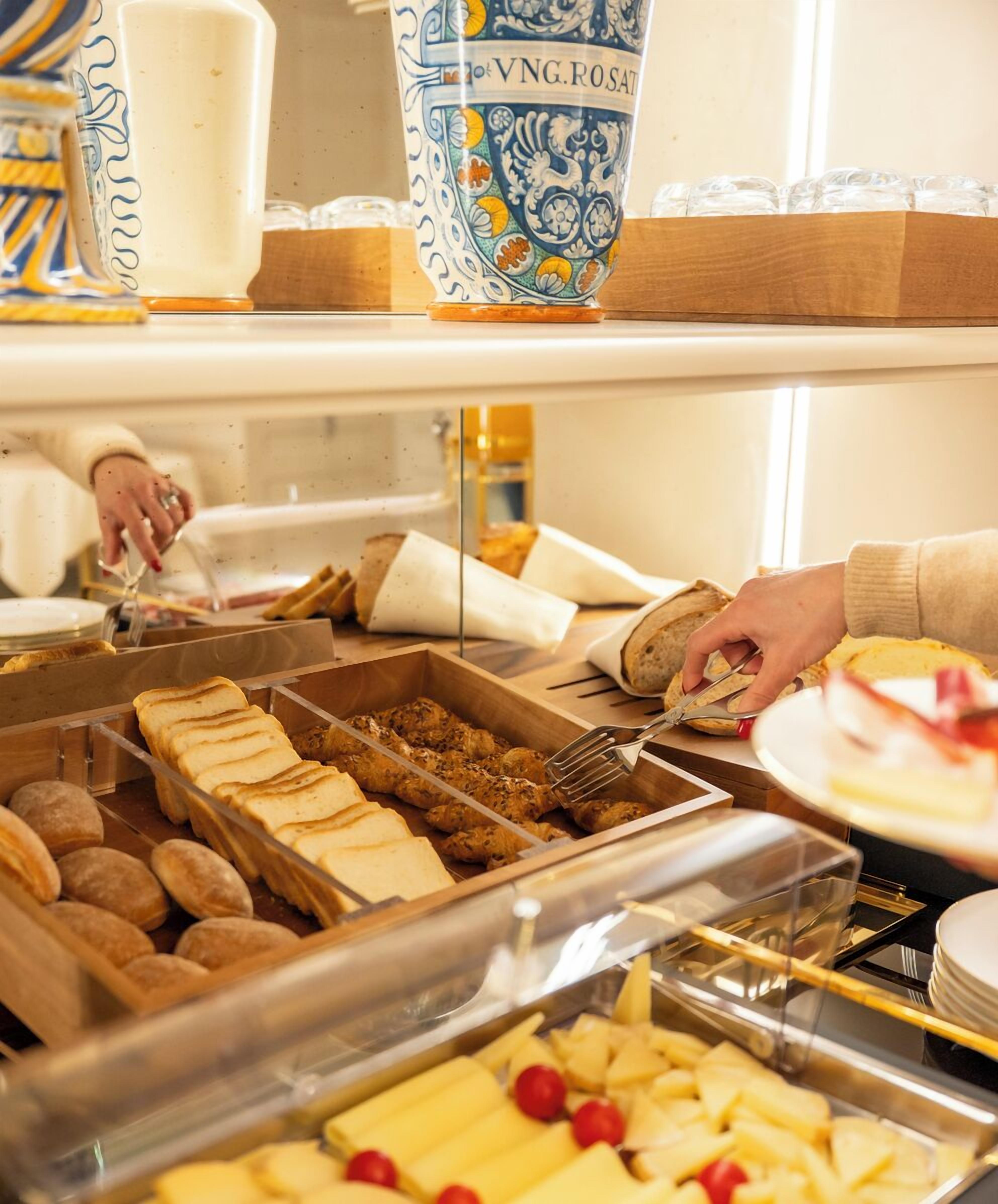 Buffet com diversos alimentos, incluindo pão, doces e frutas.