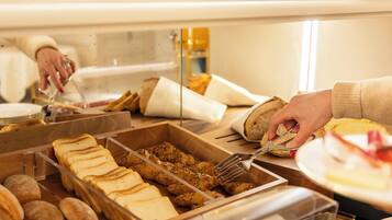 Buffet com diversos alimentos, incluindo pão, doces e frutas.