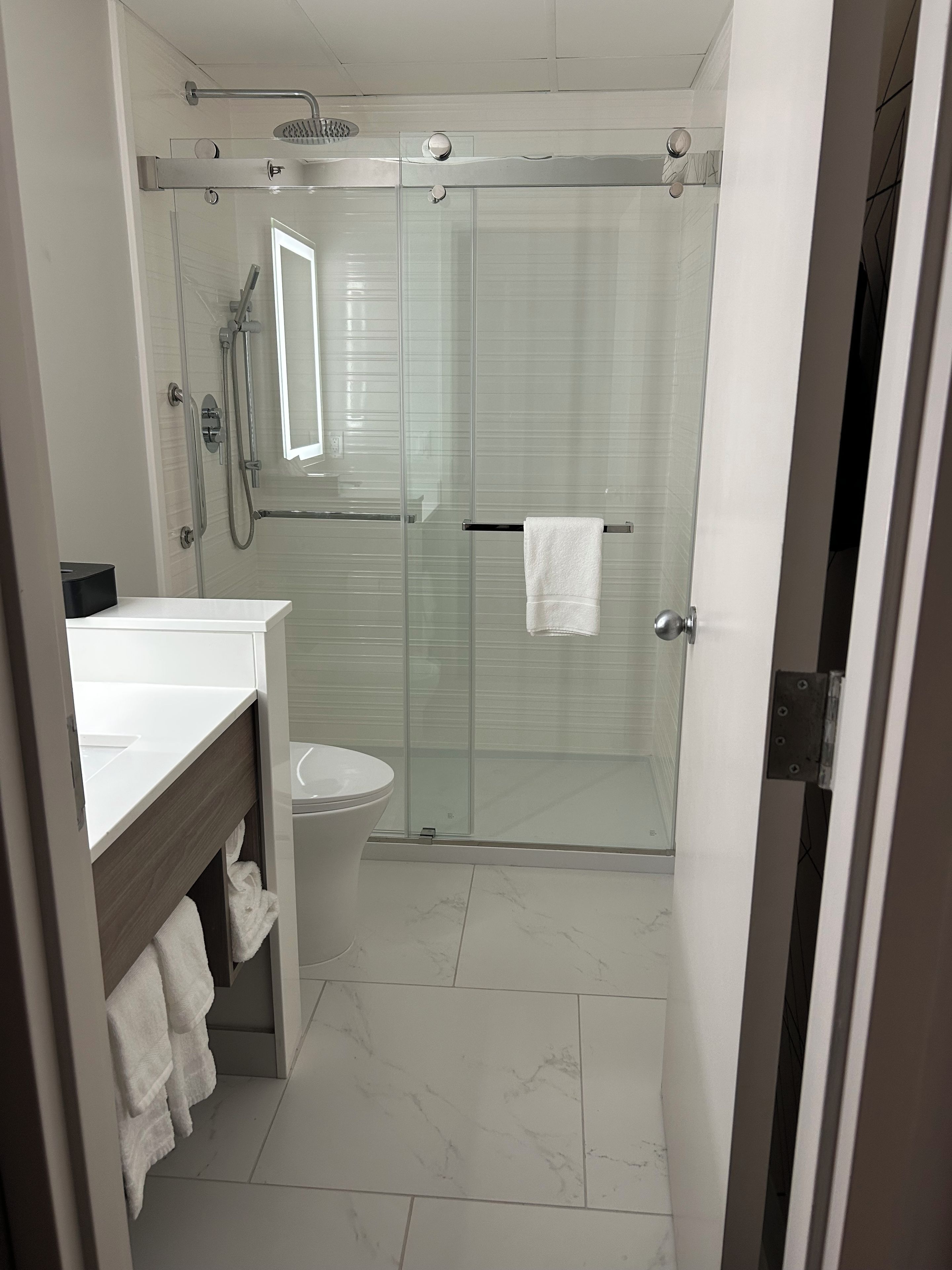 Uma casa de banho moderna com chuveiro em cabine de vidro, lavatório branco e sanita.