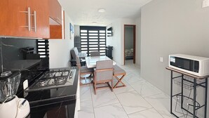 Cozinha moderna com fogão a gás, micro-ondas e área de jantar com mesa e cadeiras.