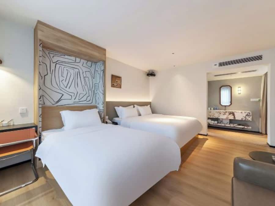 Quarto de hotel com duas camas, uma escrivaninha e um espaço de estar.