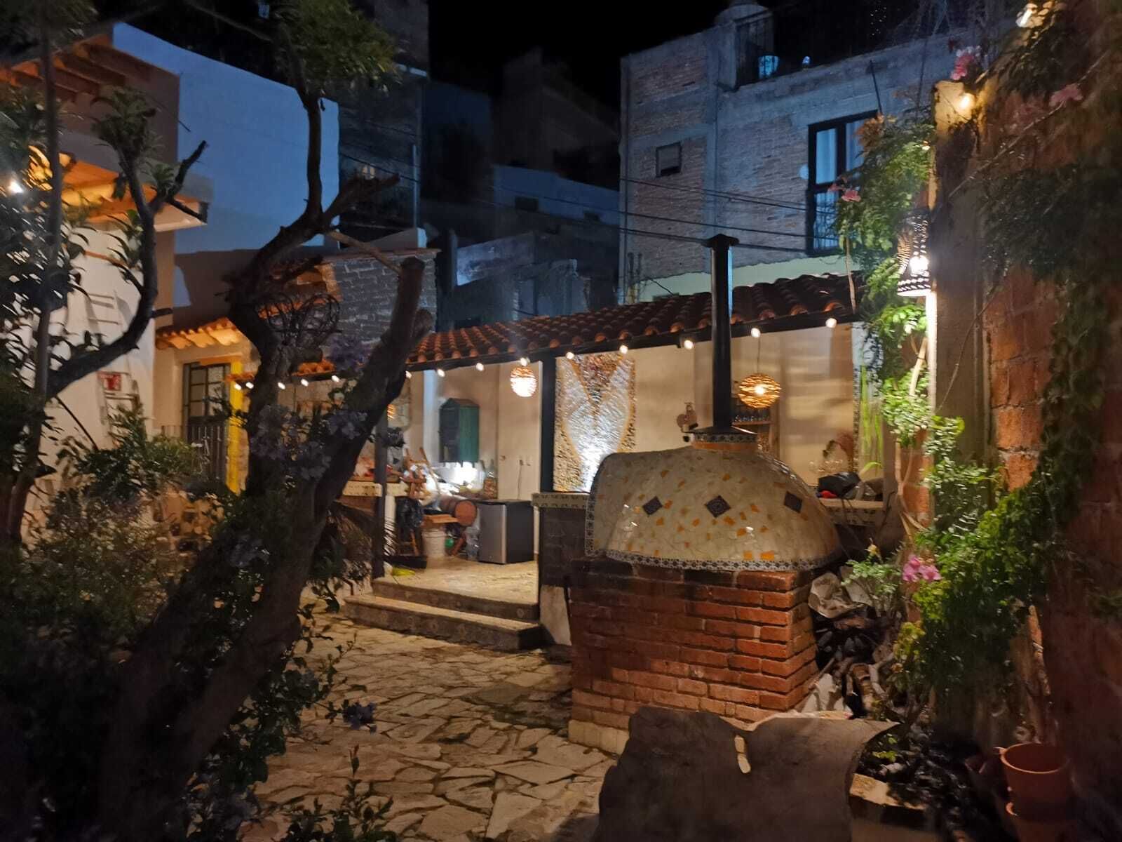 Um pátio com forno de tijolos, caminho de pedra e um edifício com telhado em telhas.