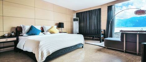 Quarto de hotel moderno com uma cama grande, uma escrivaninha e vista para o mar.